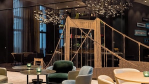 Uma área de estar moderna com escada, assentos confortáveis e um lustre decorativo.