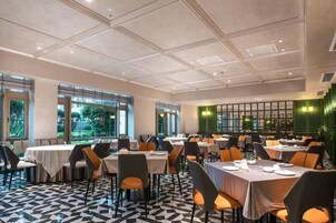 Uma sala de jantar ampla com várias mesas e cadeiras, grandes janelas e um design de teto moderno.