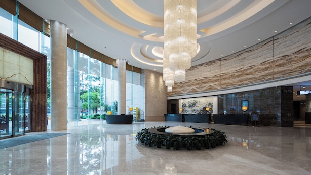 Um hall espaçoso com um grande candelabro, uma recepção e uma área de estar circular.
