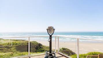 Um telescópio numa varanda com vista para a praia.