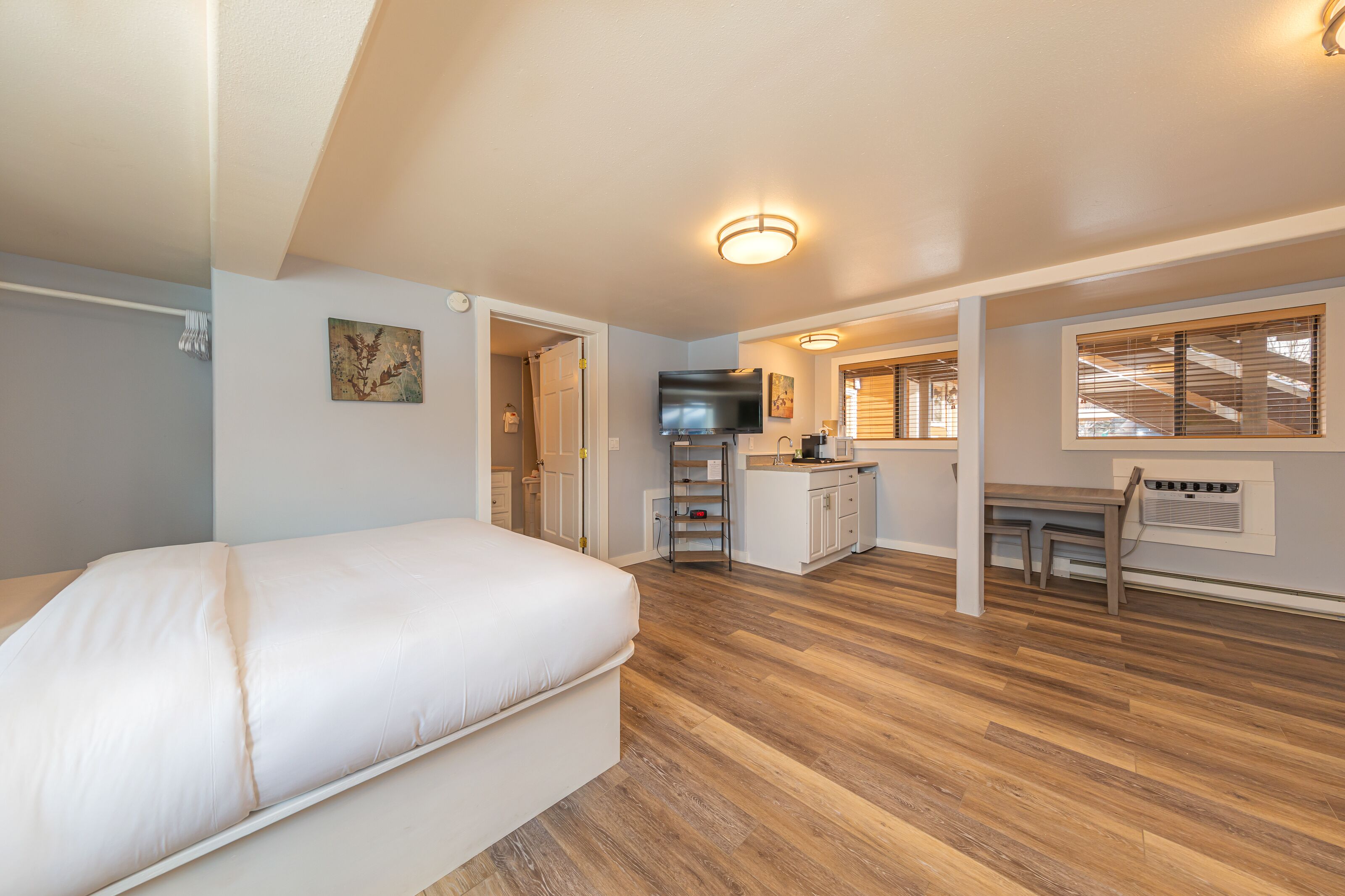 Quarto compacto com cama, cozinha compacta e área de refeições.