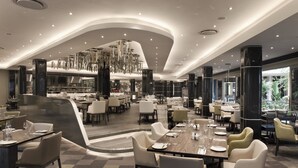 Um restaurante amplo com diversas áreas de refeição, decoração moderna e um bar central.