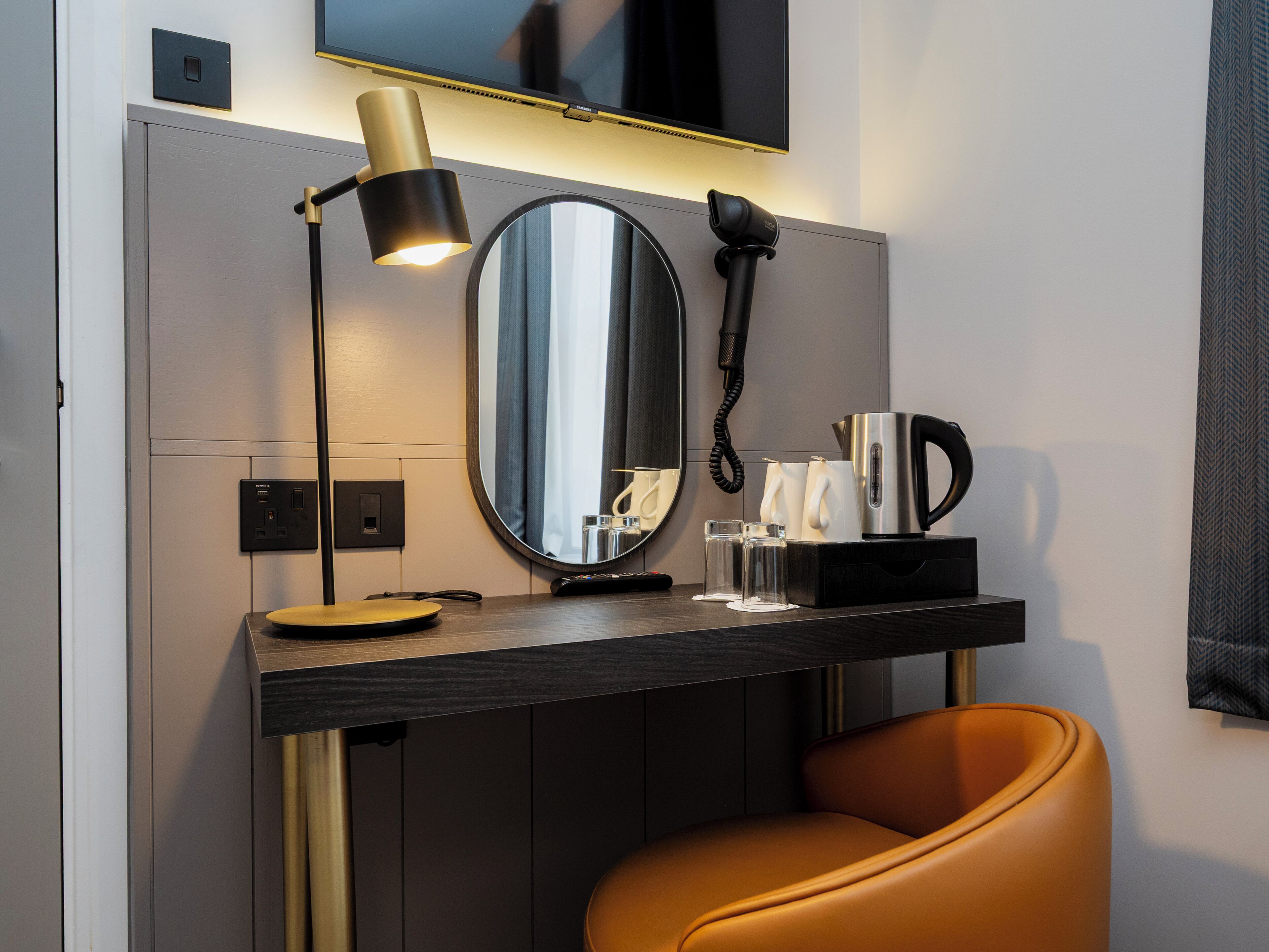 Quarto de hotel moderno com uma escrivaninha, um espelho, telefone e máquina de café.