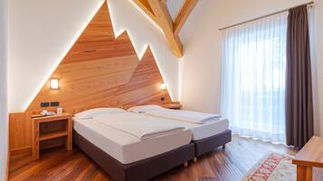 Quarto com teto de madeira, duas camas, uma mesinha de cabeceira e janela com cortinas.
