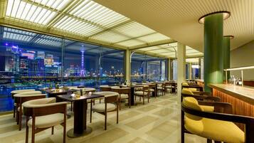 Restaurante moderno com vista para o horizonte da cidade à noite.