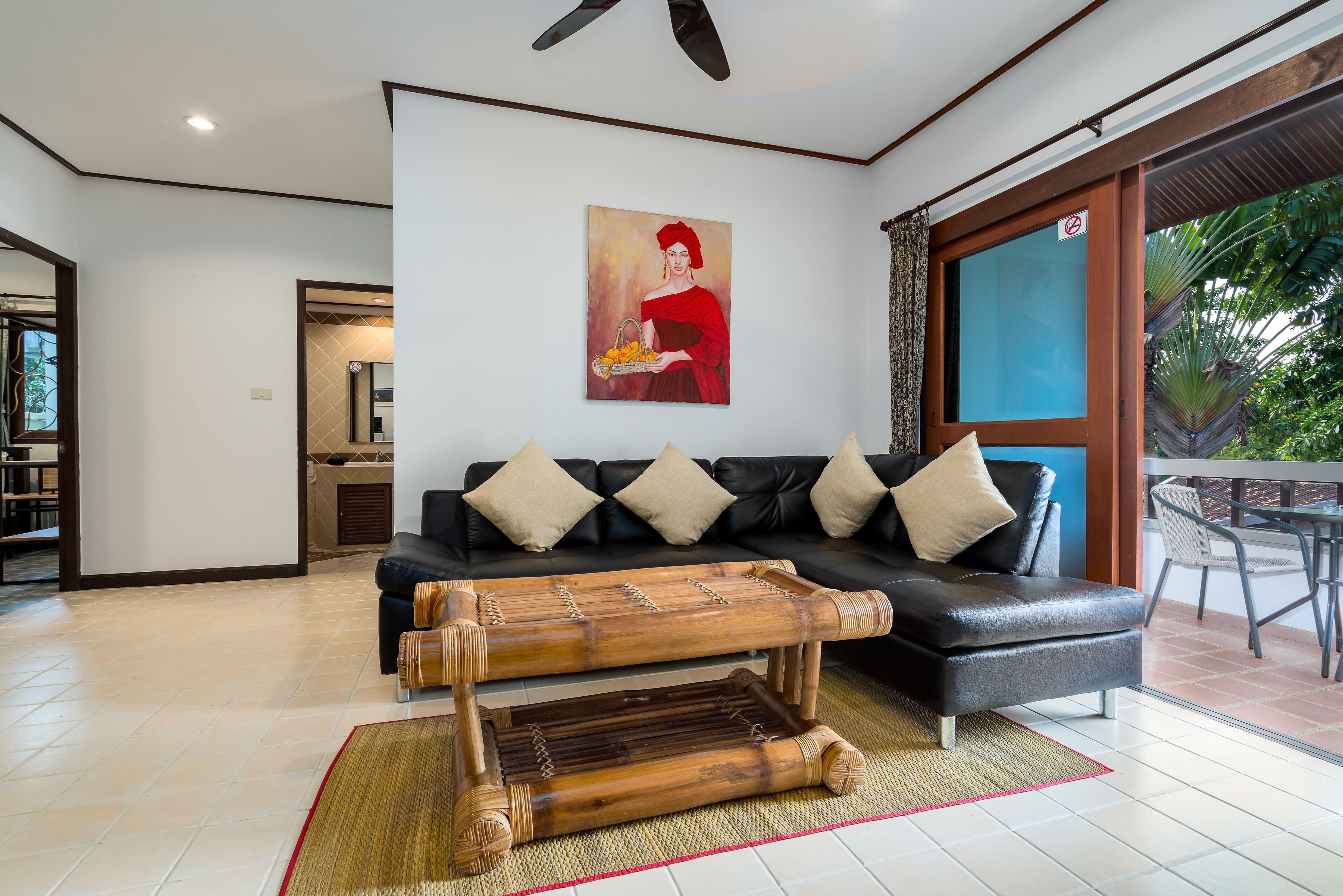 Uma sala de estar com um sofá preto, uma mesa de centro de madeira e um quadro na parede.