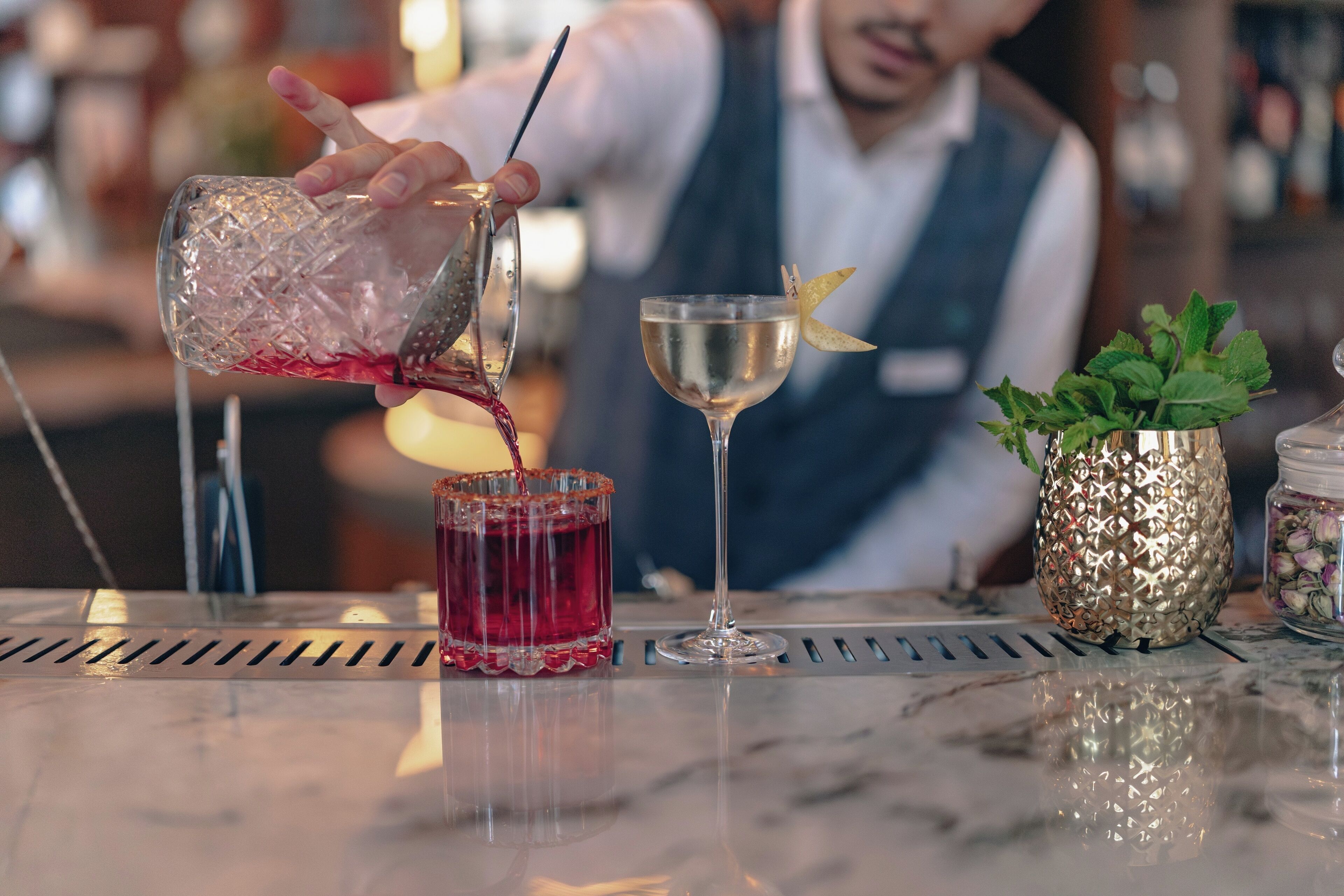 Um barman servindo uma bebida num copo.