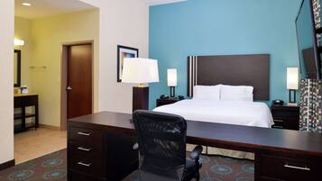 Quarto de hotel com cama, escrivaninha, cadeira e duas mesas de cabeceira com abajures.