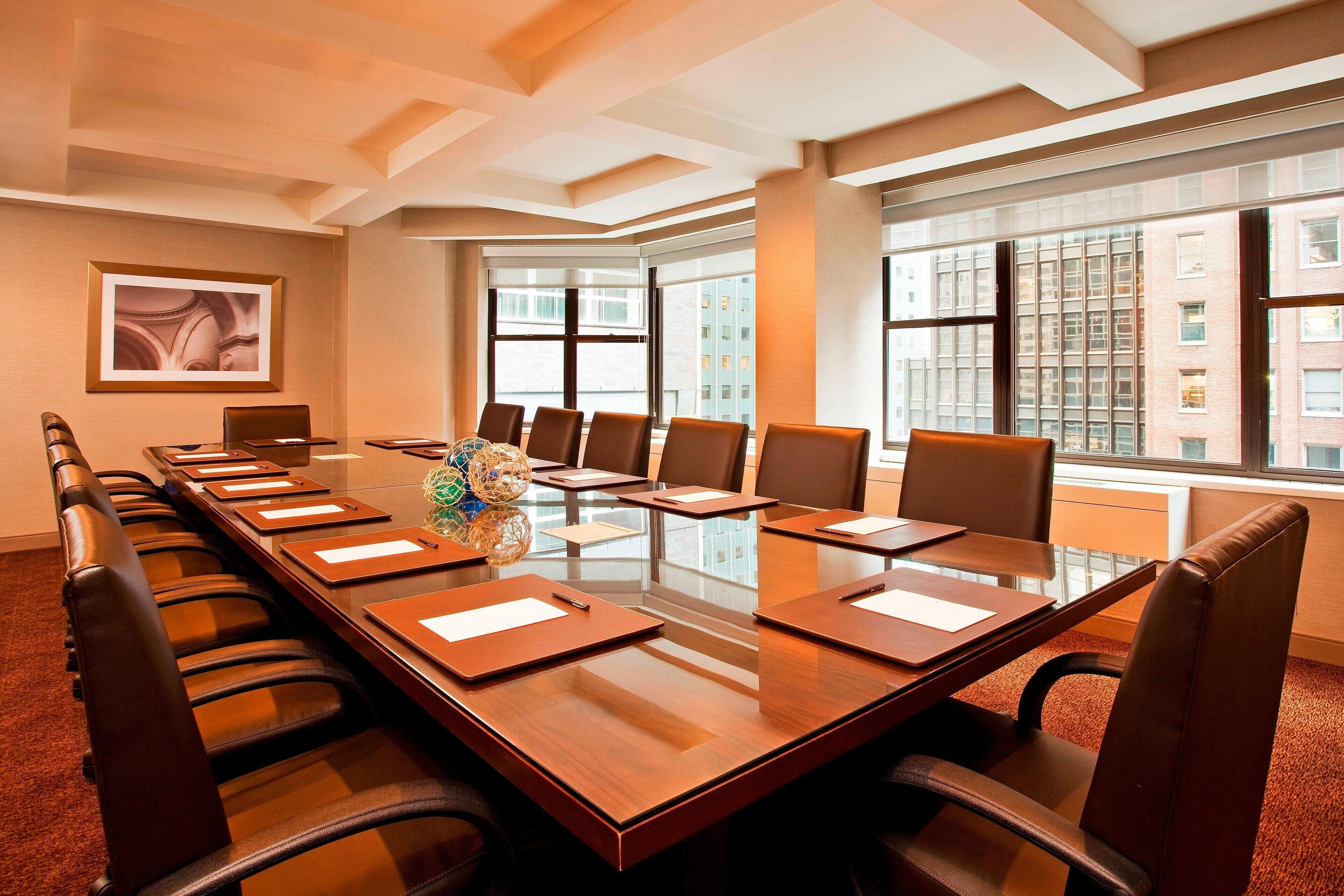 Uma sala de conferências com uma mesa comprida, várias cadeiras e janelas grandes.