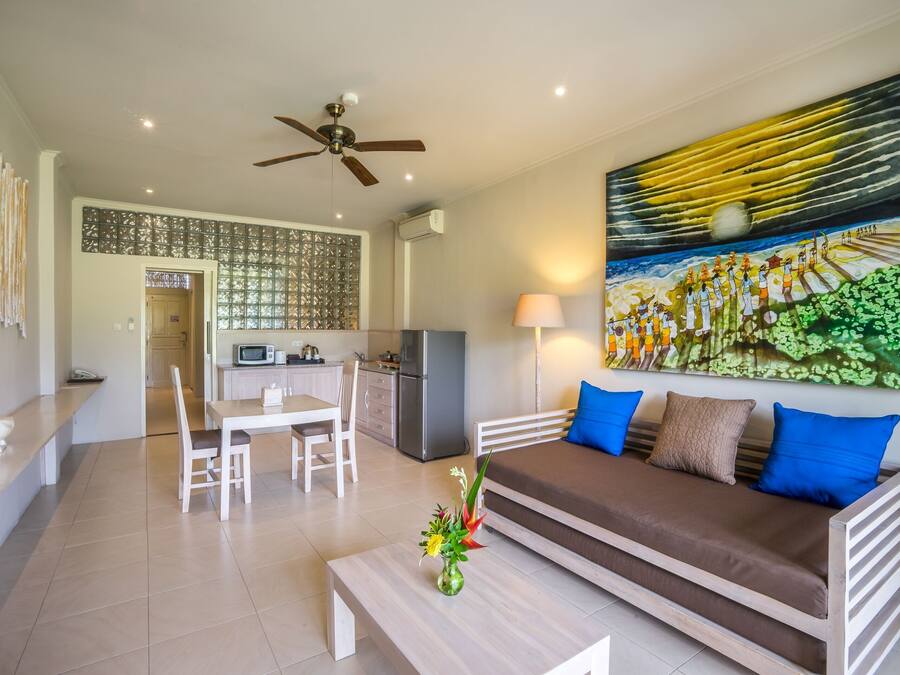 Uma sala de estar moderna com sofá, mesa de centro e área de jantar. Há um quadro na parede e um ventilador de teto.