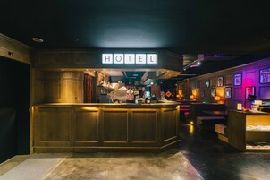 Um saguão de hotel com balcão de recepção, área de estar e bar.