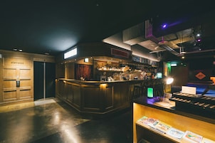 Uma área de bar com balcão, banquetas e uma estante com livros.