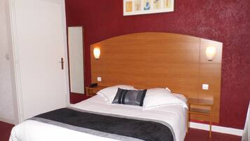 Quarto de hotel com uma cama grande, cabeceira de madeira, mesas de cabeceira e uma obra de arte pendurada na parede.