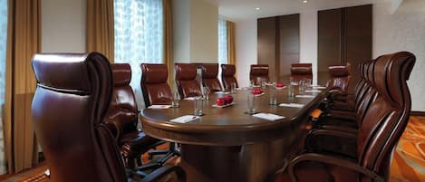 Uma sala de conferências com uma mesa redonda, oito cadeiras de couro e piso coberto de carpete.