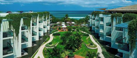 Um resort com vários edifícios, uma área central ajardinada e vista para o oceano.