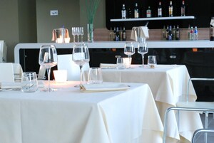 Um restaurante com mesas preparadas para refeições, cada uma com copos de vinho e talheres.