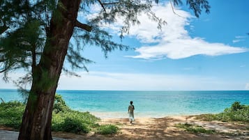 Na praia, areia branca, guarda-sóis, toalhas de praia