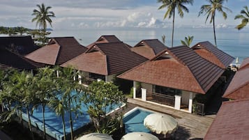Resort com vários edifícios, piscina e palmeiras.