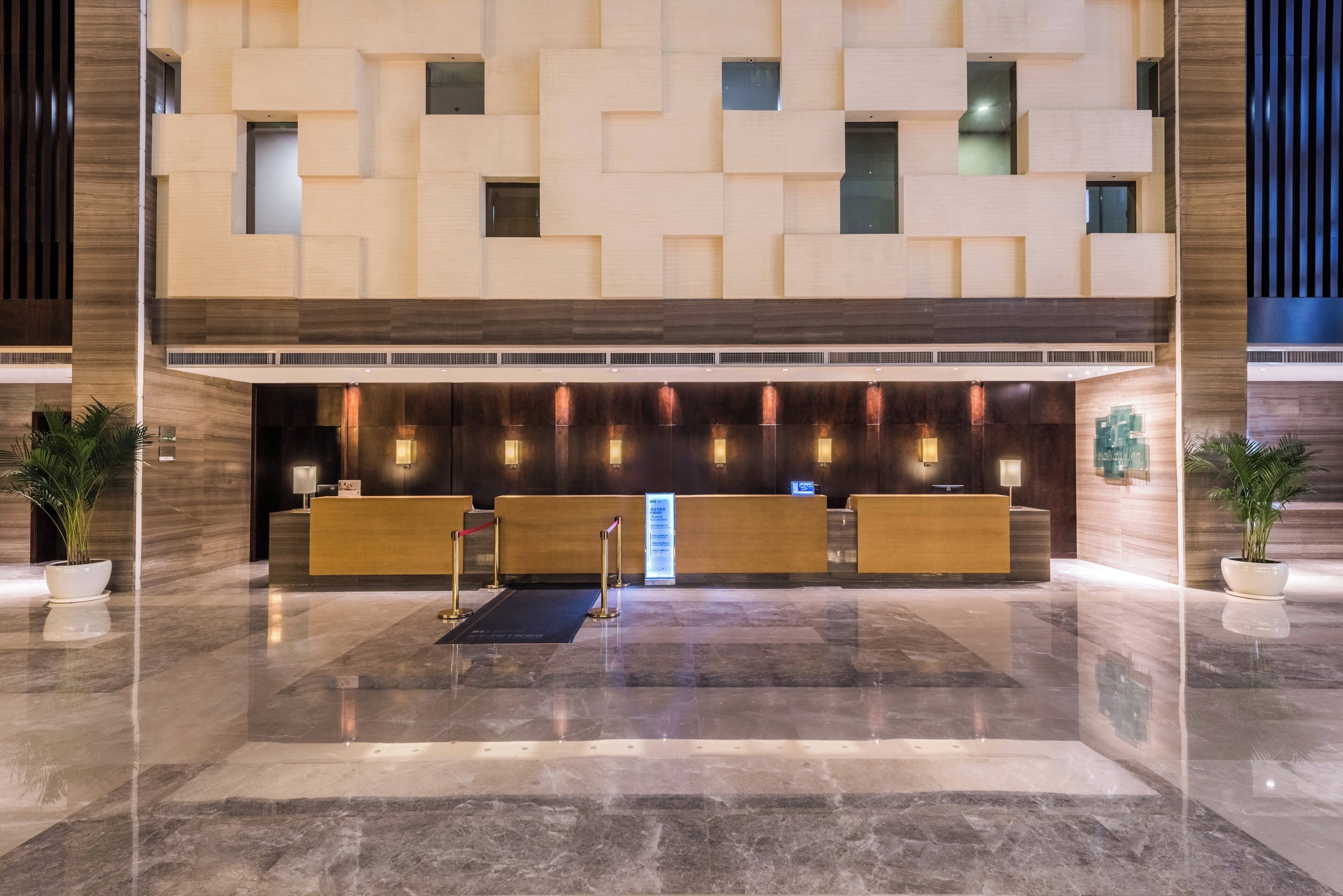 Um saguão de hotel com balcão de recepção, várias luminárias e design moderno.