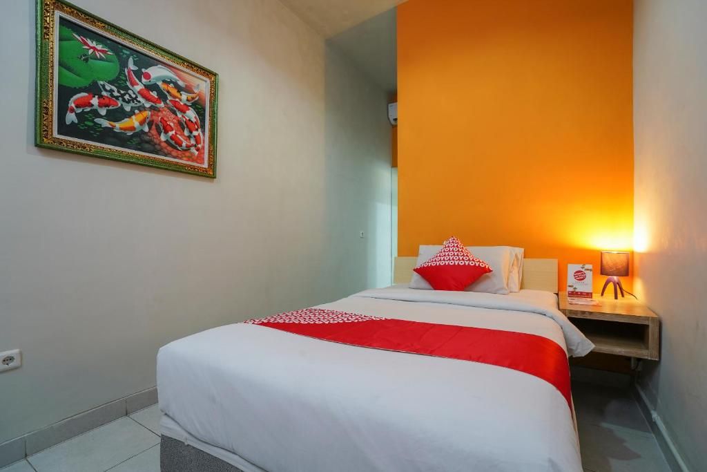 Quarto de hotel com cama, mesa de cabeceira, luminária e um quadro na parede.