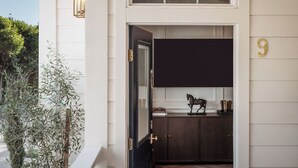 Uma casa de dois andares com uma porta preta, o número 9 na parede e um pequeno armário com objetos decorativos.