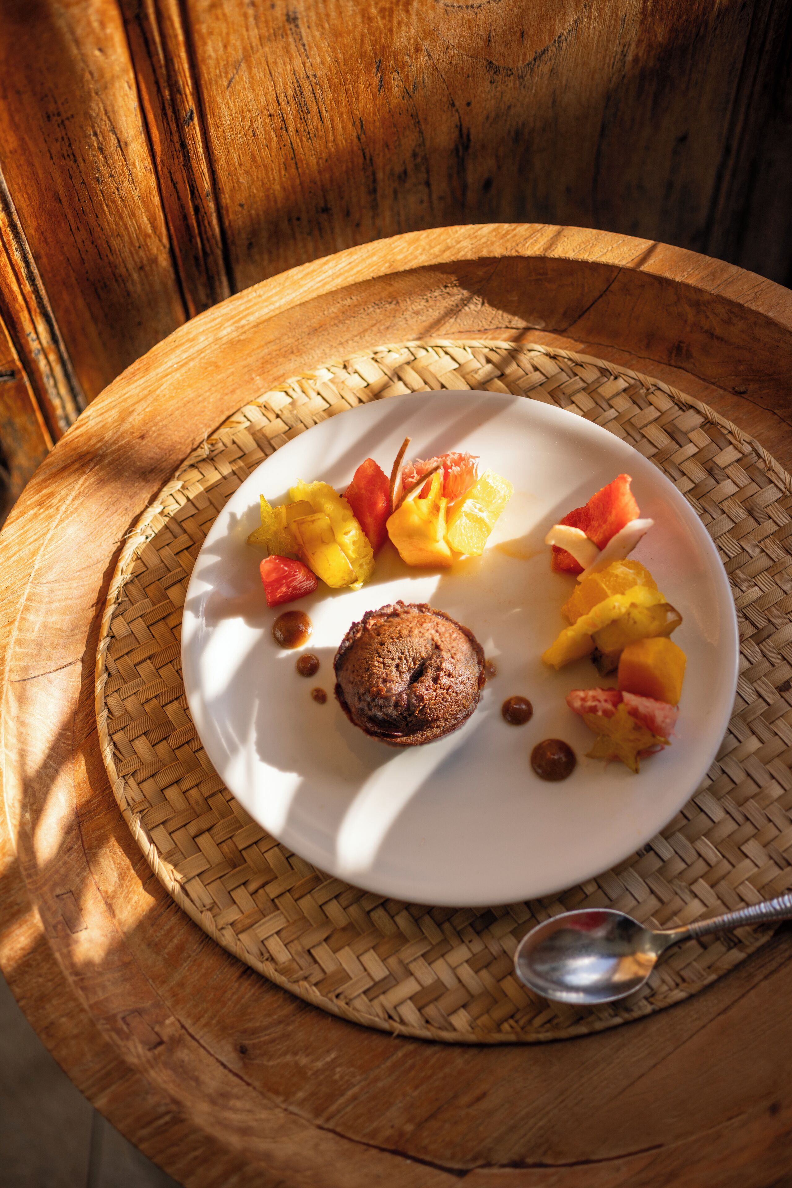 Um prato com sobremesa e fruta sobre um tapete tecido.