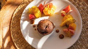 Um prato com sobremesa e fruta sobre um tapete tecido.