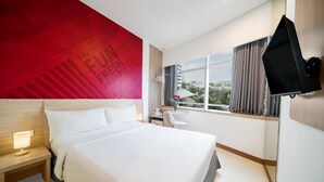 Quarto de hotel com cama, mesa de cabeceira, televisão, janela com cortinas e vista para a cidade.