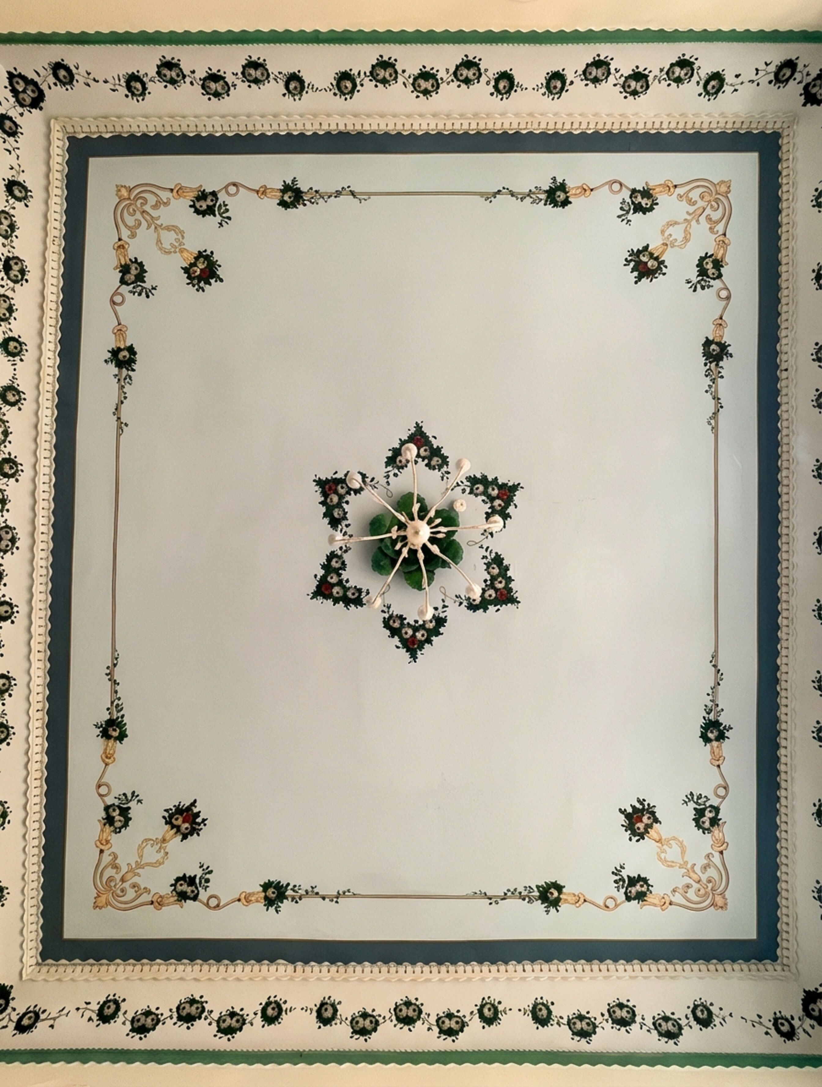 Teto com um desenho floral central rodeado por uma moldura decorativa.