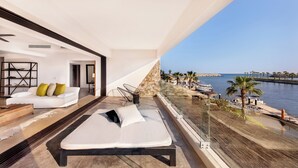 Uma varanda moderna com cama, sofá branco e mesa de centro de madeira.