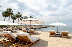 Na praia, espreguiçadeiras, guarda-sóis de praia, toalhas de praia 