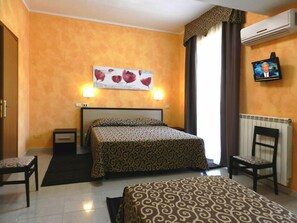 Quarto de hotel com uma cama, uma cadeira, uma televisão e um quadro na parede.