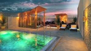 Piscina no terraço com pergolado de madeira, espreguiçadeiras e parede de pedra.