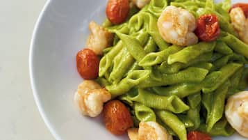 Um prato de massa com camarões e tomate cereja.