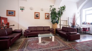 Uma sala de estar espaçosa com um amplo sofá de couro marrom, uma mesa de centro de vidro e uma grande planta em vaso.