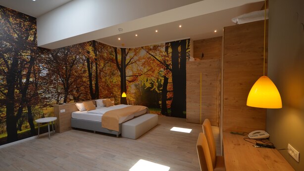 Quarto moderno com cama, mesa de cabeceira e escrivaninha com abajur.