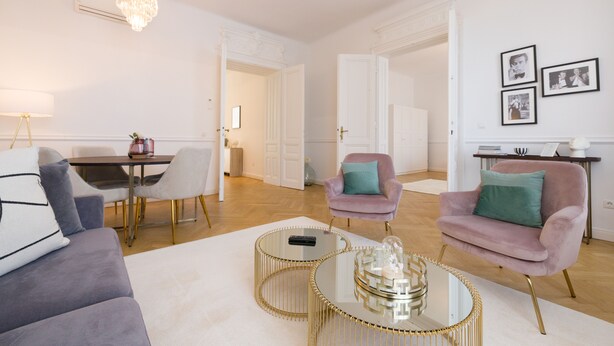 Uma sala de estar moderna com sofá, poltronas, mesa de centro e um espaço de jantar com cadeiras e mesa.