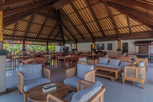 Uma área de refeições ao ar livre, com mobiliário de madeira e teto alto.