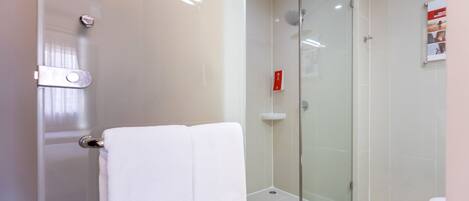 Um banheiro moderno com box de vidro, vaso sanitário branco e porta-toalhas com duas toalhas brancas.