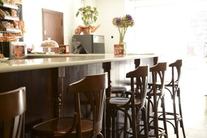Uma área de bar com cadeiras de madeira e um balcão com diversos itens.