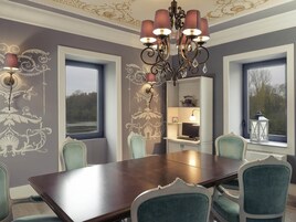 Uma sala de jantar com uma mesa grande, cadeiras, um lustre e painéis decorativos na parede.