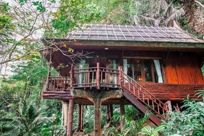 Uma cabana de madeira com varanda, rodeada por uma floresta densa.