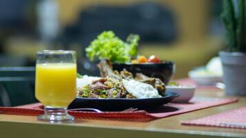 Uma mesa de jantar com um prato de comida, um copo de suco de laranja e uma pequena tigela.