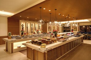 Buffet com diversos alimentos, teto de madeira e iluminação pendente.