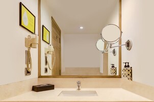 Uma casa de banho com um espelho grande, uma pia, um secador de cabelo e um telefone.