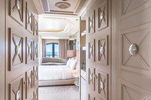 Quarto de hotel luxuoso com uma cama grande, área de estar com vista e varanda.