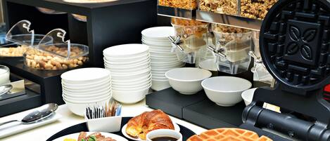 Buffet com diversos alimentos, incluindo cereais, doces e waffles.