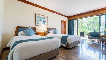 Quarto de hotel com duas camas, uma janela grande com vista, uma cadeira e uma mesa.