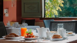Uma mesa de café da manhã com pratos de comida, um jarro, xícaras e um copo de suco de laranja.