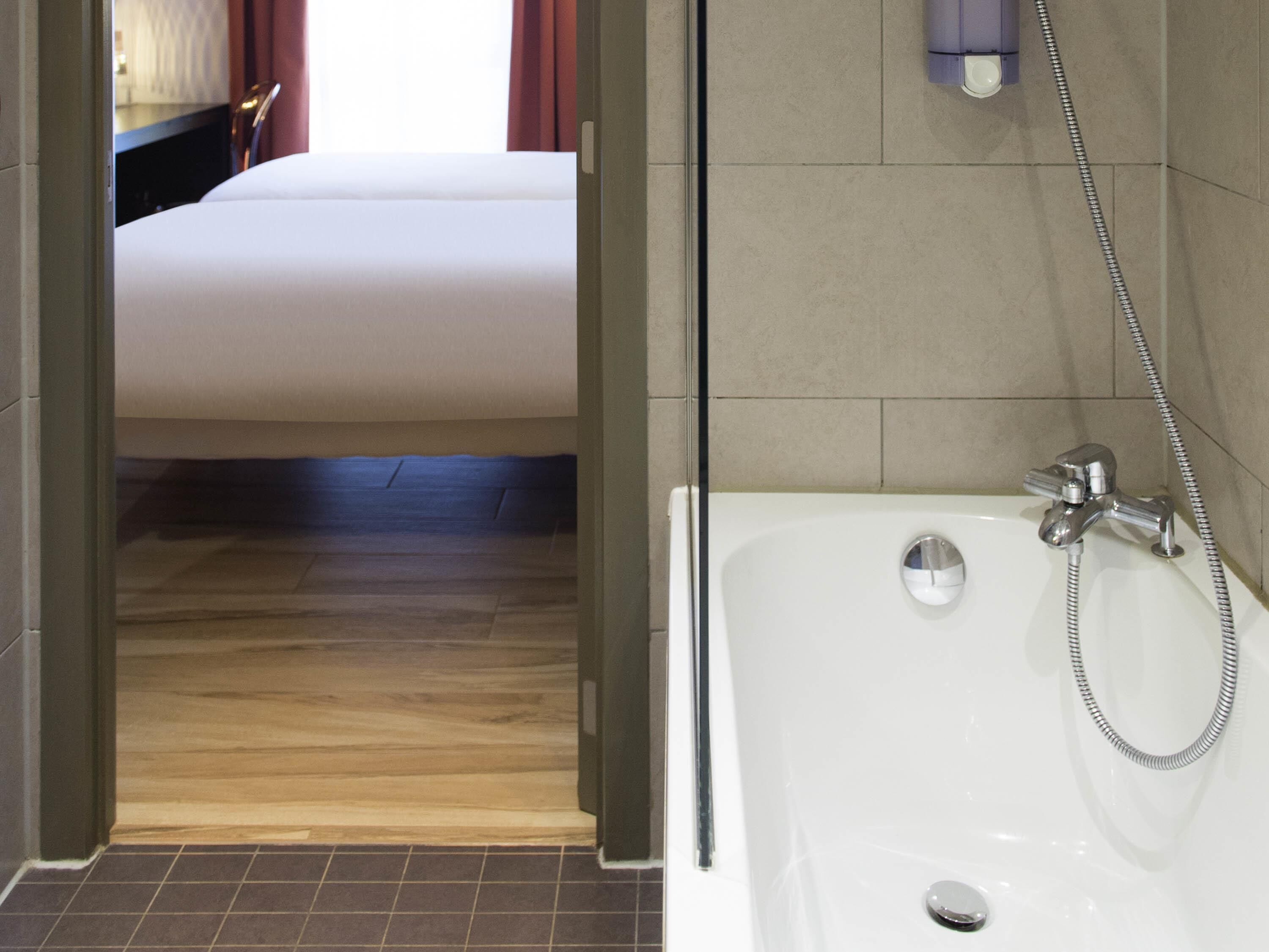 Quarto de hotel com cama, chuveiro e vista para o exterior.